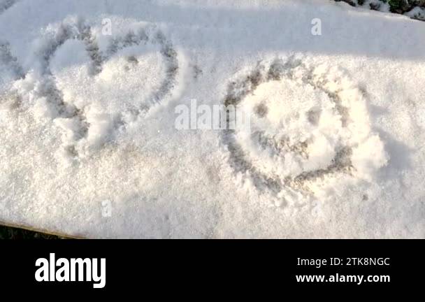 drawing in the snow. man draw on the snow. Child drawing heart shape on ...