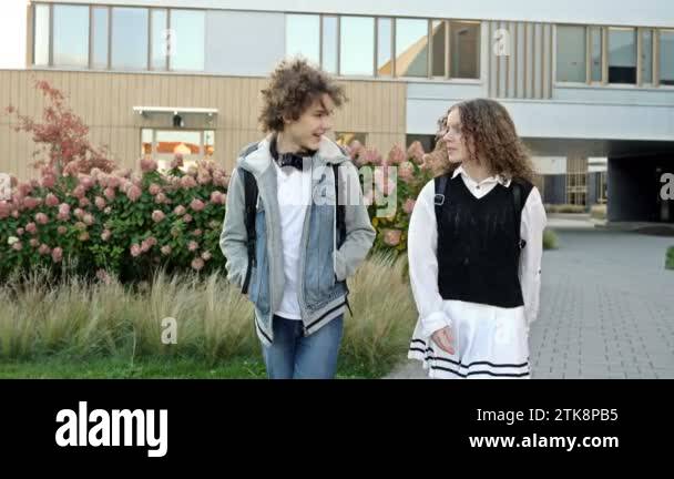 Two cute high school students, a guy and a girl, are walking around the ...