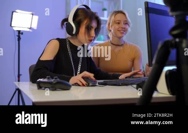 Concentrated serious millennial woman gaming as blurred friend talking ...