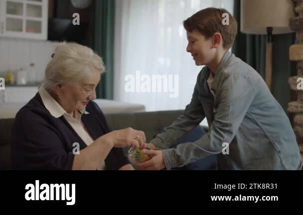 Boy offering candy in bowl to his elderly grandmother.Little boy ...