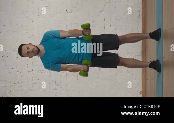Vertical video. Athletic male fitness coach doing exercises at the home ...