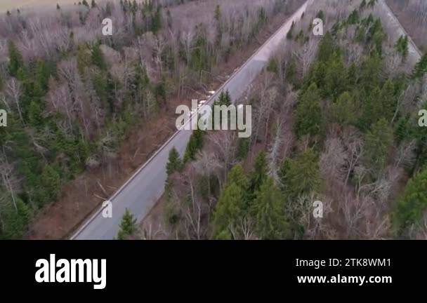 A birds eye view of a red car driving fast on a fast paved freeway ...