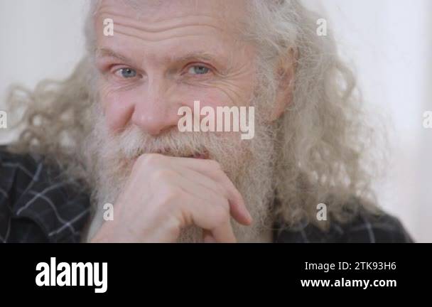 Close-up front view of handsome senior Caucasian man touching long grey ...