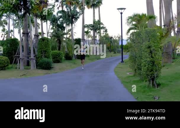 Asian women running in a public green park with palm trees in Pattaya ...