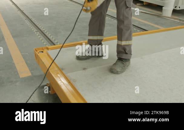 Worker connecting the parts of the iron profile with screws.A factory ...