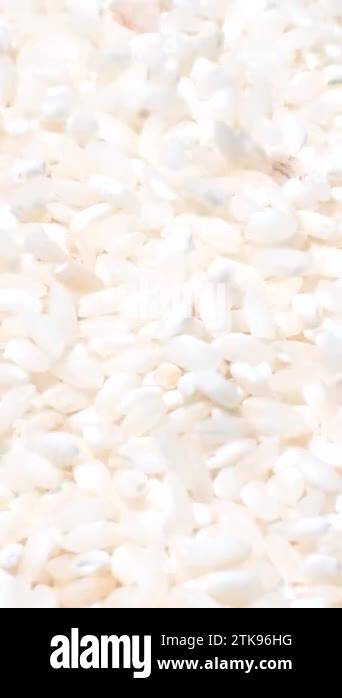 White uncooked rice crumbles and rotates in a circle. Cooking in China ...
