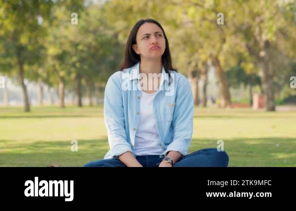 Curious Indian girl thinking in a park, sitting on the ground Stock ...
