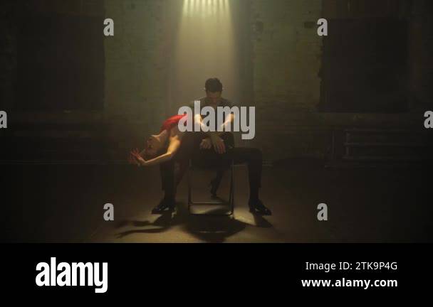 Empty loft room,young man sits on chair in center,woman starts dancing ...