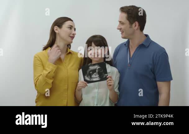 Young parents and their daughters look at ultrasound film approaching ...