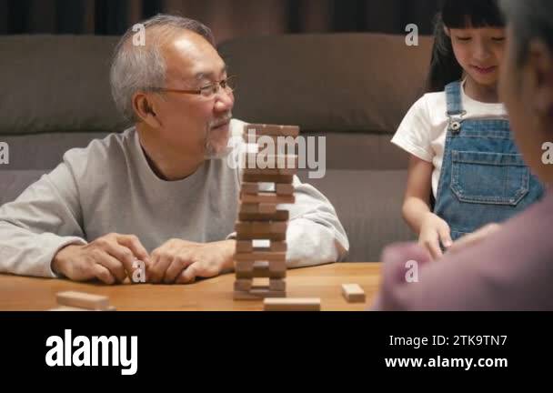 Smiling parent having fun play build constructor tower of wooden blocks, Happy grandparents ...
