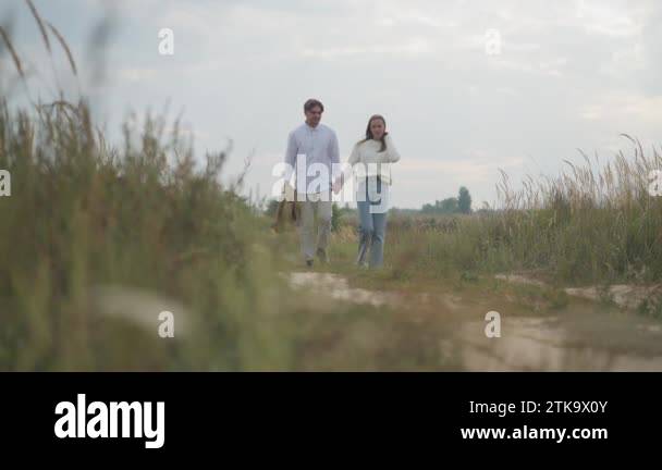 Wide shot young man strolling with woman covering spouse with jacket in ...