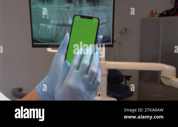 Closeup dentist hands sterile glove hold green screen cellphone at ...