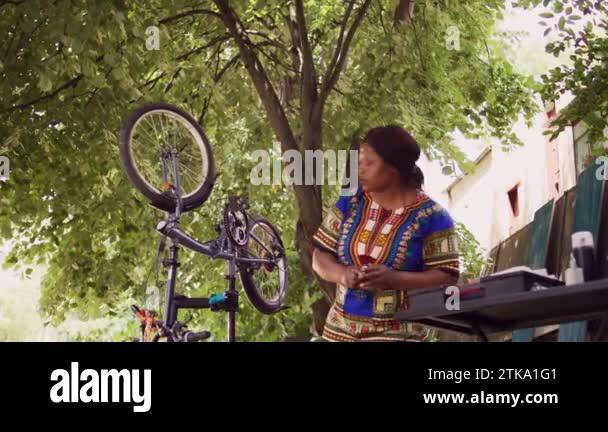 Healthy black woman mending her own bicycle using specialized equipment ...