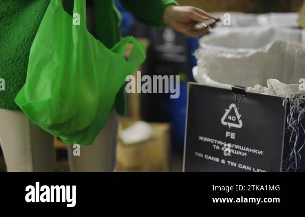 Unrecognizable young woman placing tin cans from plastic bag into box ...