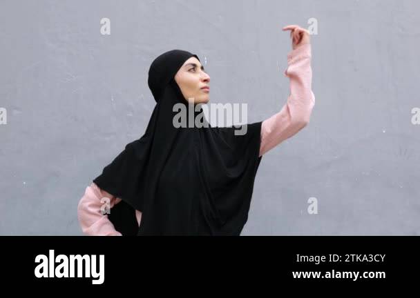 Islamic Muslim woman in black hijab and pink shirt stands in confident ...