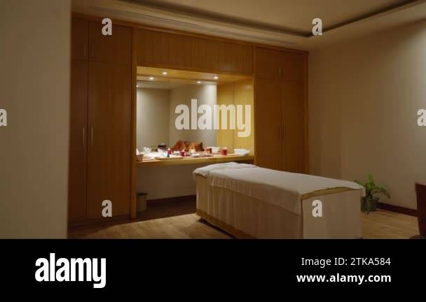 Massage bed in the middle of spacious spa room with big wall mirror and ...