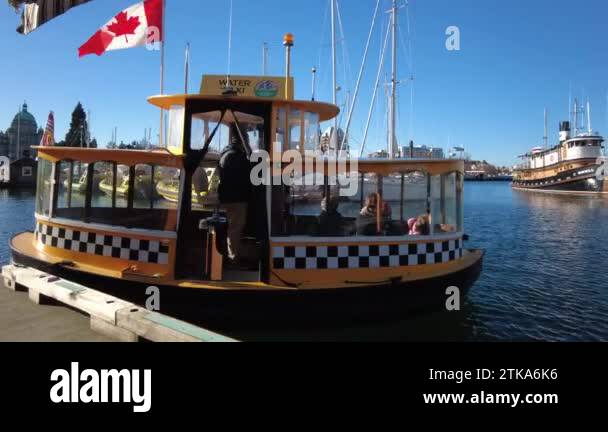 A yellow water taxi with passengers pulls away from the dock and heads ...