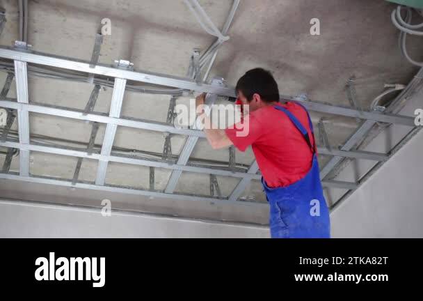 Man in uniform install framework for hung ceiling by screwdriver Stock ...