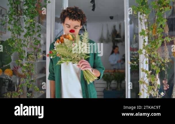 Handsome african man enjoy flowers composition in plant shop. Dreamy ...