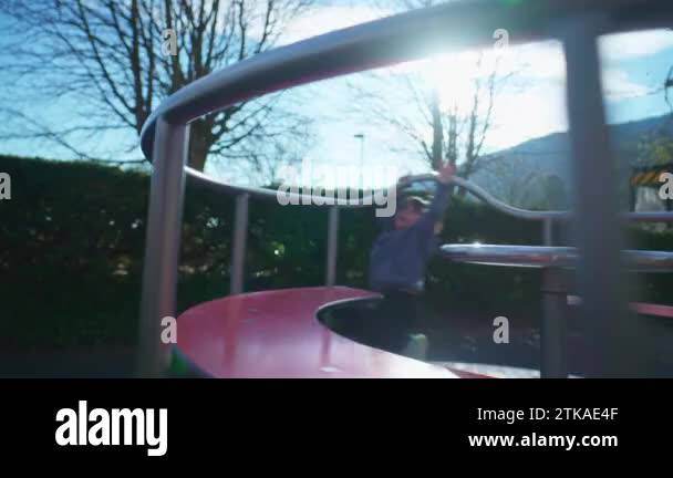 Little boy gleefully whirling on playground carousel, Kid enjoying a ...