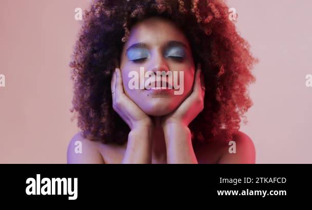 Happy biracial woman with dark hair in blue and pink light, slow motion ...