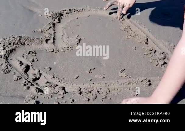 Children's hands playing in the sand Using your hands to draw a heart ...
