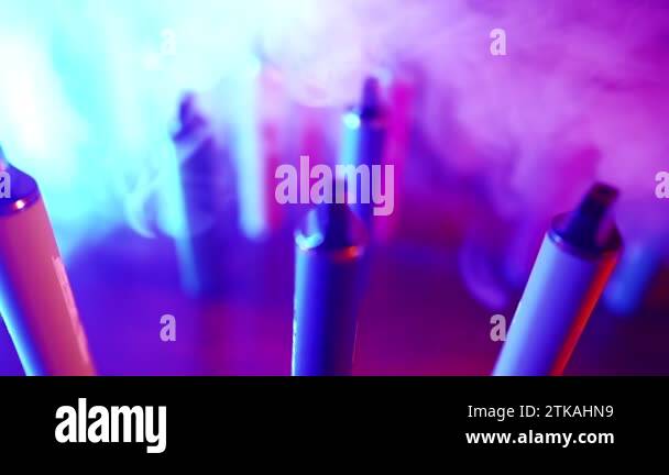 Lots of E-cigarettes and Vapes in Neon Lighting and Smoke. Concept of ...