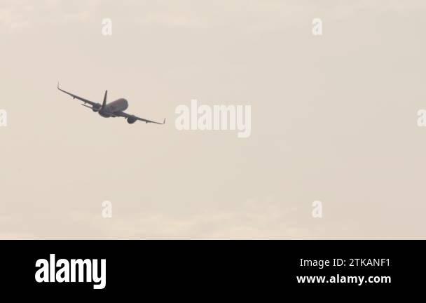 Long shot rear view of a jet passenger plane turning in the sky ...