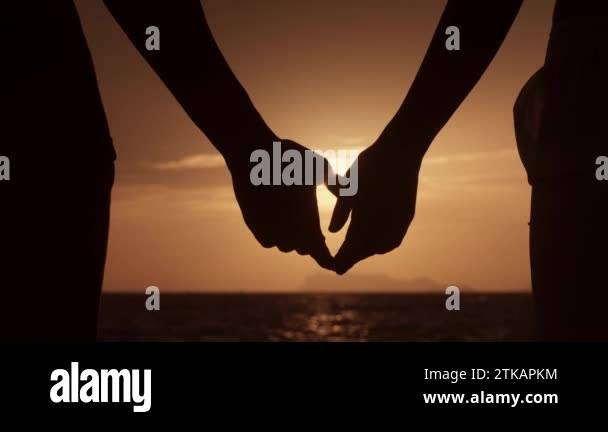 Close-up silhouette of man extending his hand and a woman takes his ...