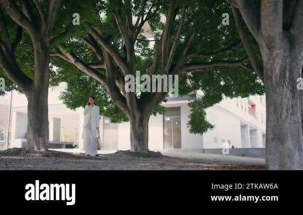 Chic lady standing square calling wearing elegant white suit. Young ...