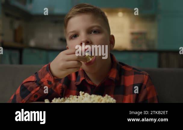 Kid Eating Popcorn Looking At Camera. Boy watching TV with popcorn ...