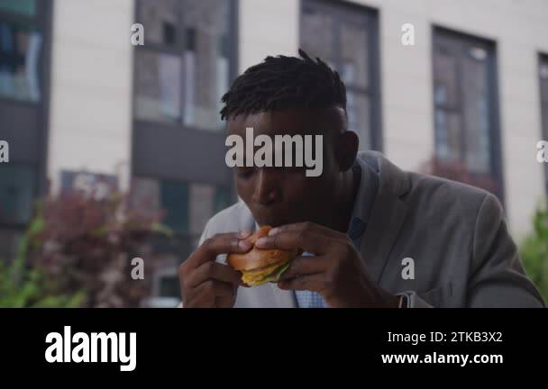 Black Man Eating Burger Outside. African American Businessman eating ...