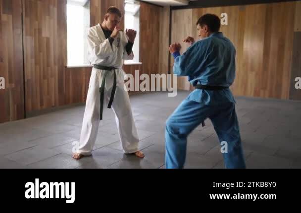 Martial arts men in kimonos practice kicks and punches. Male fighters ...