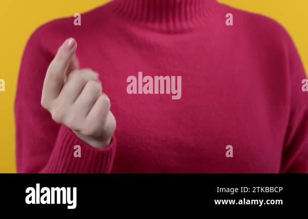 Unrecognizable woman snaps fingers on yellow red studio background ...