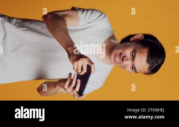Vertical video: Happy male model playing video games on smartphone ...