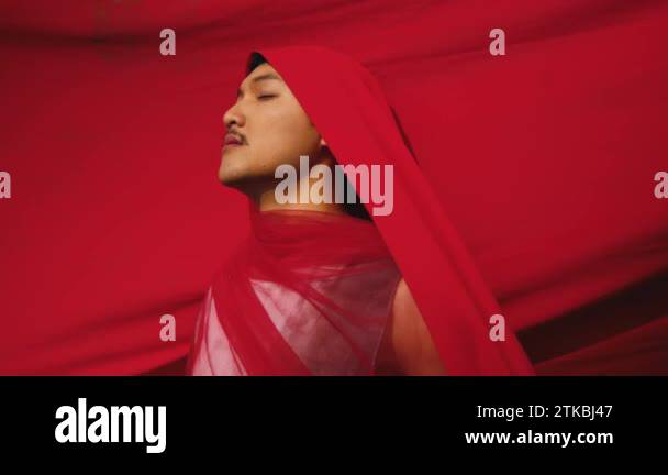 an Asian man bound and strangled by a red cloth with a resigned face in ...