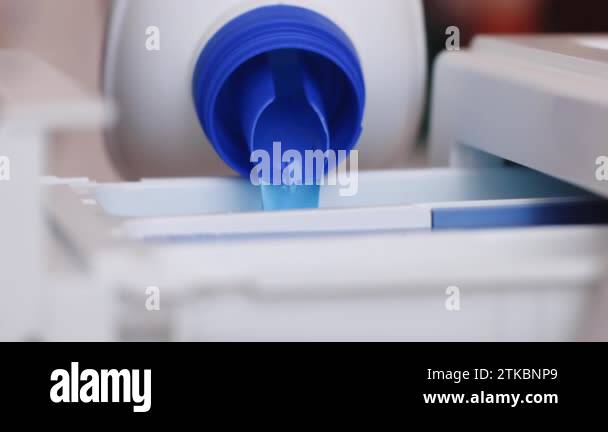 Woman pours necessary amount of liquid laundry detergent into ...