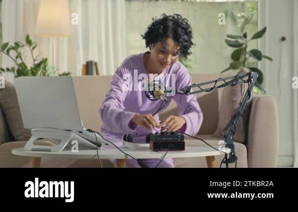 Asian gen Z girl smiling while setting up recording equipment and ...