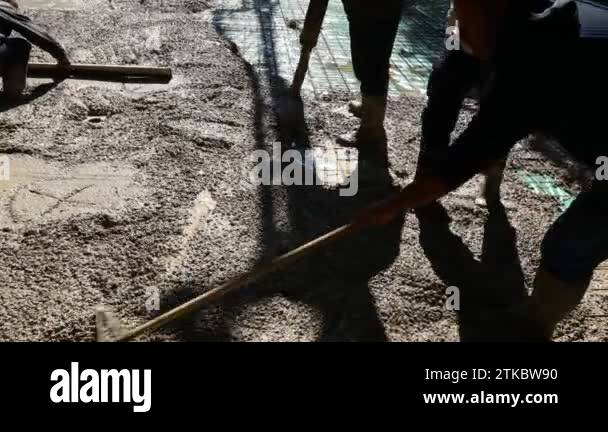 Construction worker is directing pump tube, pouring layer of concrete ...