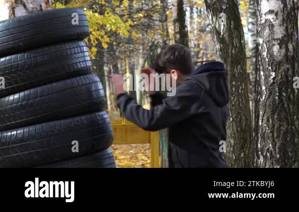 A boy boxing training on the park punching a punch bag hanging from a ...