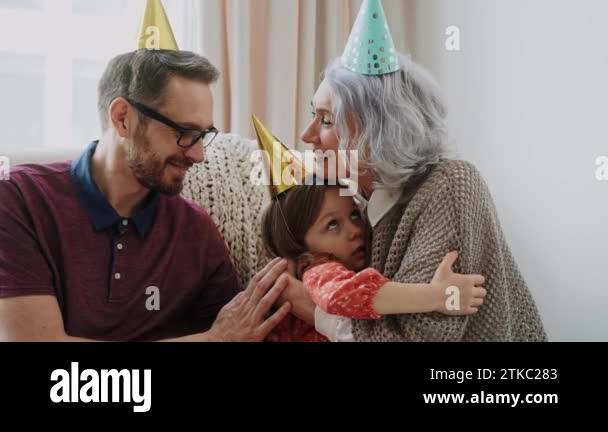 Young girl has fun and cuddles with her father and grandmother at ...