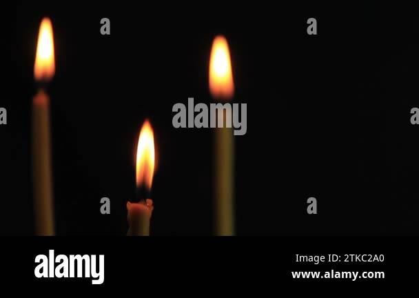 peaceful candle flame on the dark. The candle burns with a soft yellow ...