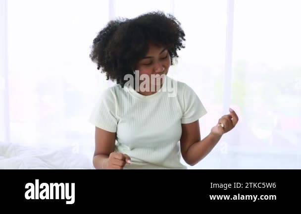 African American woman sits on bed in her bedroom at her health care ...