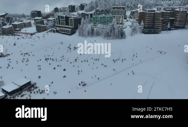 Many skiers and snowboarders skiing down on snowy mountainsides slopes ...