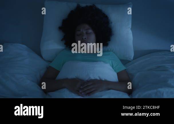 Young female laying in bed sleeping, suddenly woken up by nightmare ...