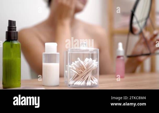 Pretty woman with towel on head dripping cosmetic serum on facial skin ...