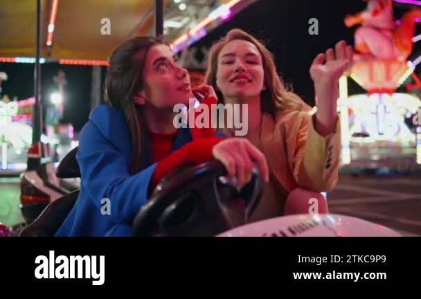 Girls rest amusement park in illuminated carousel closeup. Two smiling ...