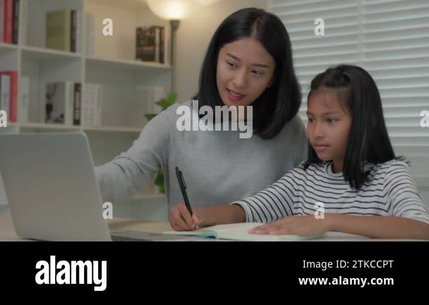Mother teaching lesson for daughter by laptop. Asian young little girl learn at home. Do ...