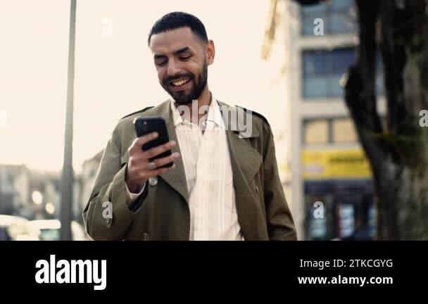 A happy Middle Eastern man laughing at content online holding cellphone ...