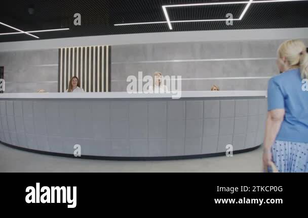 Elderly couple come to reception desk in clinic waiting room and make ...